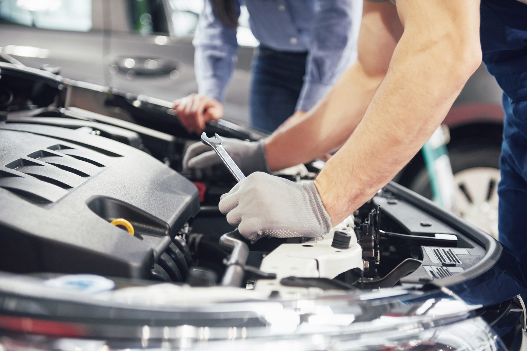 A man mechanic and woman customer look at the car hood and discuss ...